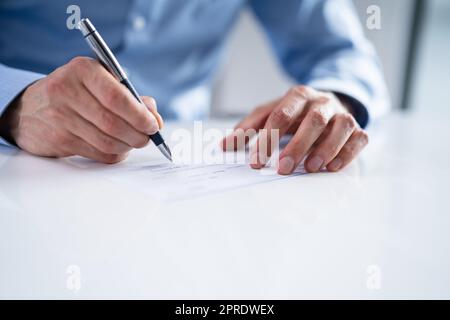 Writing Cheque. Signing Paycheck Or Money Check Stock Photo - Alamy