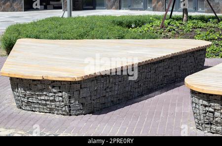 Wooden benches from gabion baskets with stones inside. Wood mounted on ...