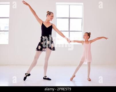 Cute little girl ballerina and her teacher doing exercises in ballet ...