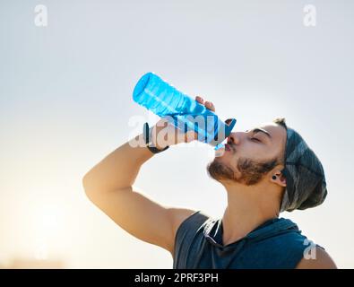 It fuels a better workout. a sporty young man drinking water while ...