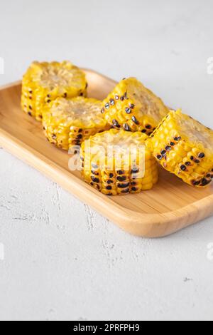 Grilled corn on the cob with slices of lemon over white wooden ...