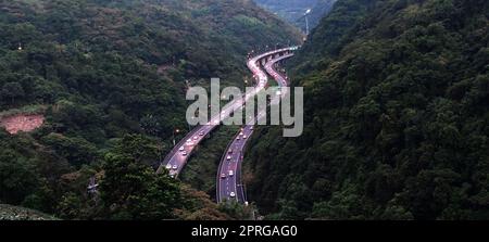 The curved highway through the green rice fields with houses scattered ...
