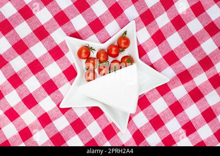 brie cheese and cherry tomatoes on a red tablecloth Stock Photo - Alamy
