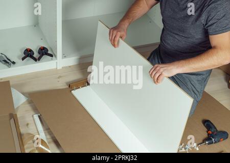 Male hands hold and insert bottom of white drawer, assembling dresser ...
