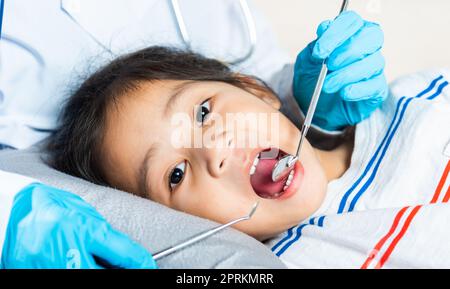 Dental kid health examination. Asian dentist making examination procedure for cute little girl ...