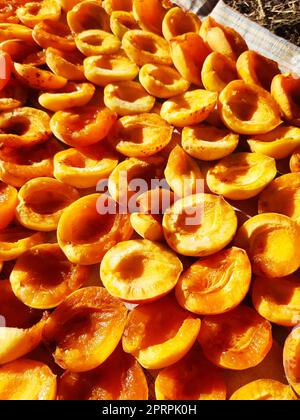 A close up food photo of an apricot cut in half with the pit on a white ...