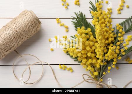 Beautiful mimosa flowers and twine on white wooden table, flat lay ...