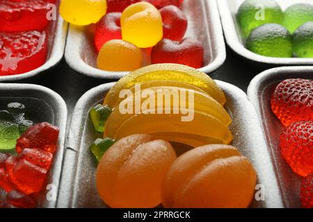Different delicious gummy candies in bowls on white background, closeup ...