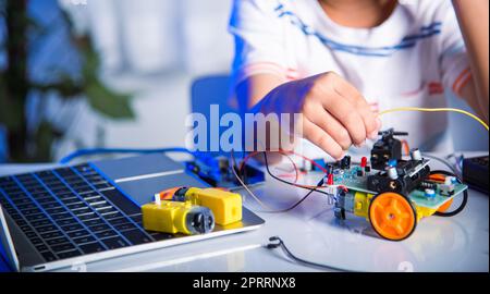 Asian kid boy plugging energy and signal cable to sensor chip with ...