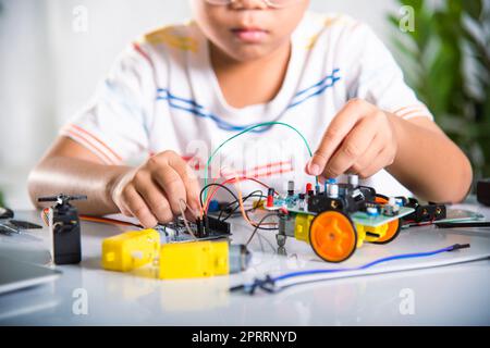 Asian kid boy plugging energy and signal cable to sensor chip with ...