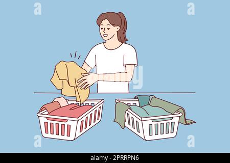Woman sorting dirty clothes for washing. Girl gathering laundry in ...