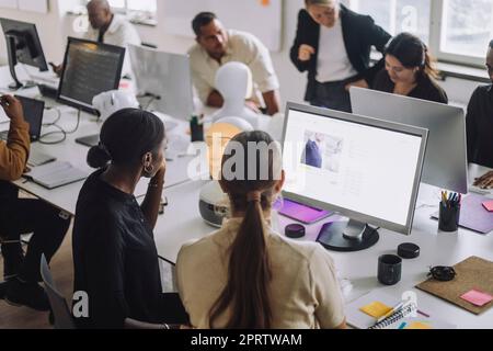 Multiracial female PhD students discussing over computer in innovation ...