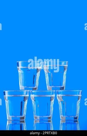 front view water glasses stacked on top of each other on light blue ...