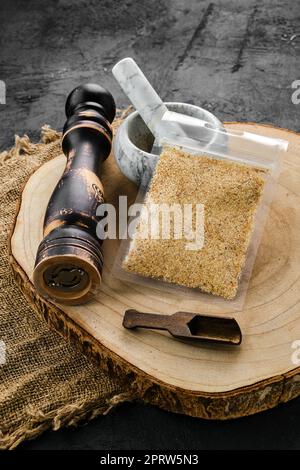 Wooden cross section with garlic in plastic package and mortar and mill ...