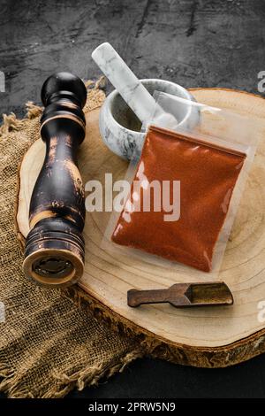 Wooden cross section with chilli pepper in plastic package and mortar ...