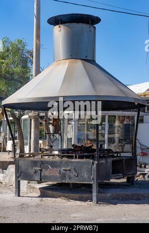 A wood-fired parrilla or grill being fired up to roast chivito, or goat ...