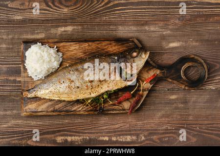 Yellow tailed mackerel with rice baked in oven on wooden cutting board ...