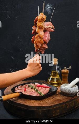 The hand holds the raw pork meat on the gray. A grown man and a piece ...