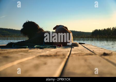 Dog lovers lying on a jetty and looking at the lake in Sweden ...