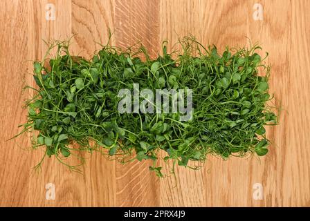 Green microgreen peas on the wooden table, grown at home. Healthy food ...
