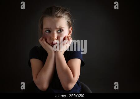 Little girl with bruises on face against dark background. Domestic ...