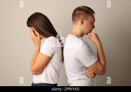Unhappy young couple turning their backs on each other against light ...