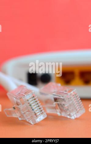 Internet router and Internet cable plugs lie on a bright orange ...