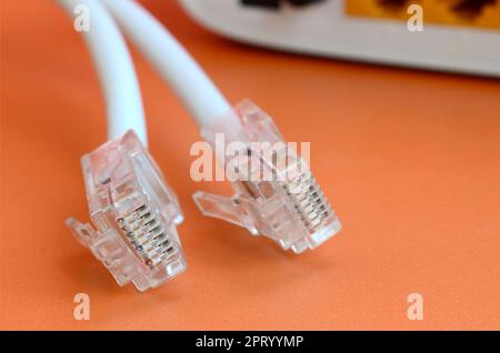 Internet router and Internet cable plugs lie on a bright orange ...