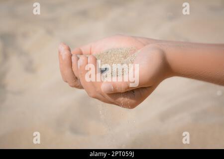Child pouring sand from hands outdoors, closeup. Fleeting time concept ...