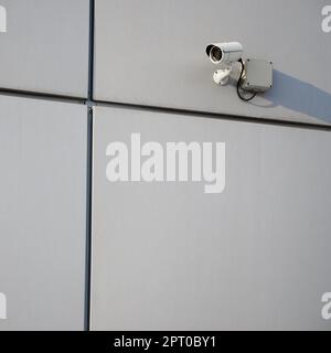 White surveillance camera built into the metal wall of the office ...
