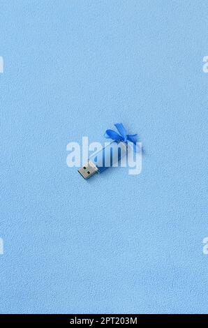 Brilliant blue usb flash memory card with a blue bow lies on a blanket ...