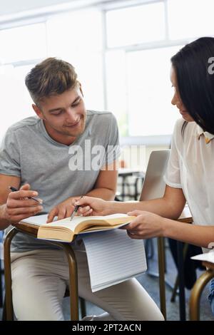 Helping out a classmate. Two students helping each other in a varsity ...