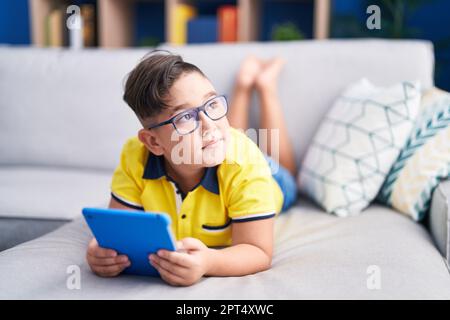Adorable hispanic boy using touchpad sitting on floor at home Stock ...