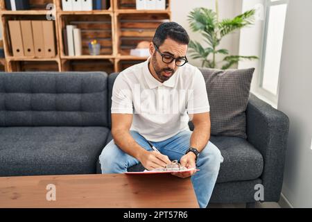 Young hispanic man psychologist having therapy session using touchpad ...