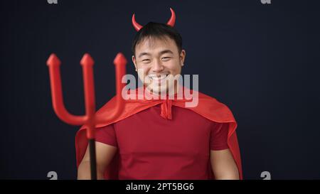 Young chinese man wearing devil costume holding pumpkin lamp over ...