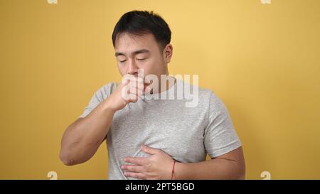Young chinese man coughing over isolated yellow background Stock Photo ...