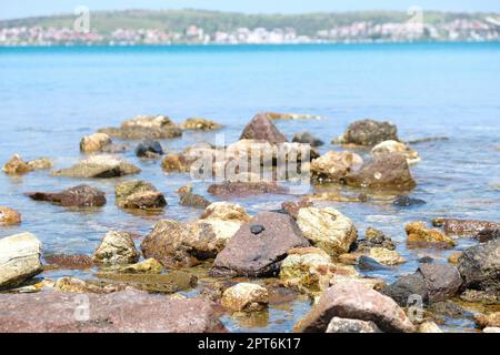 Knee feet ground-level view of pebble stone rock sea beach with faraway ...