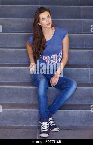 Chilling on the stairs. Portrait of a beautiful young woman sitting on ...