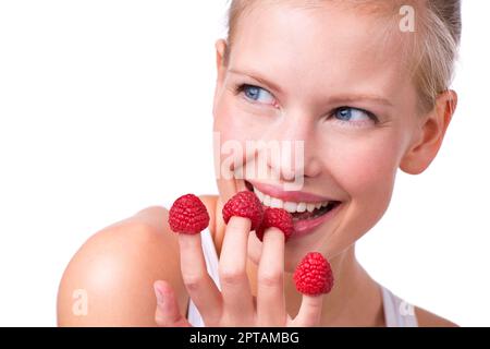 Natures play food. a beautiful young woman playfully eating raspberries ...