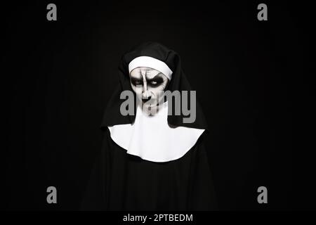 Portrait of scary devilish nun on black background. Halloween party ...
