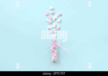 Violet and white marshmallow pieces is sprayed from a small glass ...