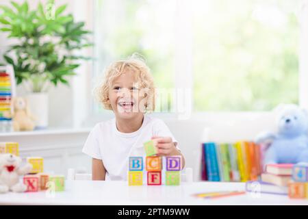 Child learning letters and numbers. Kid with colorful wooden abc blocks ...