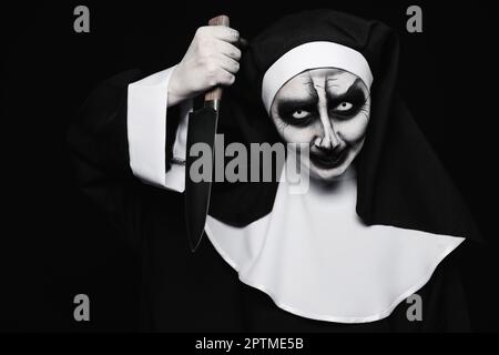 Scary devilish nun with knife on black background, space for text ...