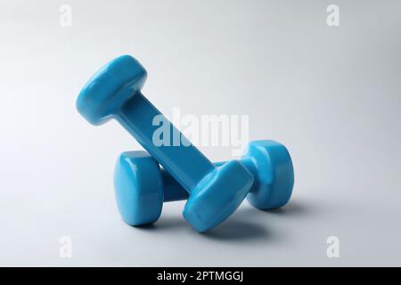Two new blue vinyl dumbbells on light background Stock Photo - Alamy