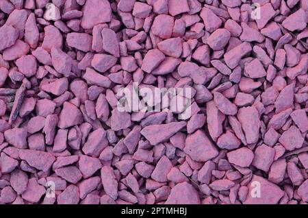 Gravel pile with white gray pink stones in front of brown wooden fence ...