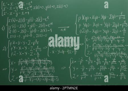 Chalkboard with many different math formulas on white wall, closeup ...