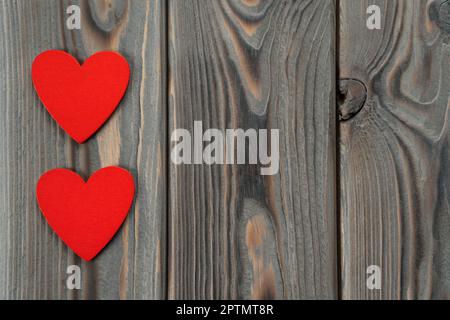 Small red hearts dancing and moving in the circle on dark wood ...