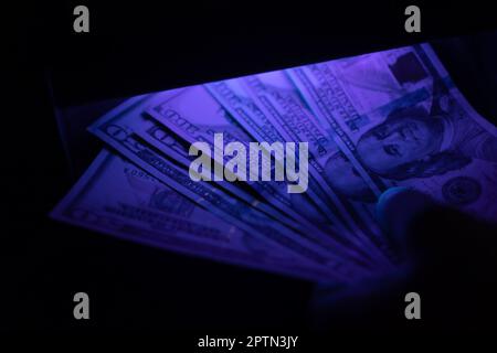 Close-up of dollars under an ultraviolet lamp. Inspection of a dollar ...