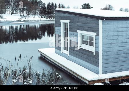 Floating cabin on the begins to freeze lake . Winter landscape. A ...