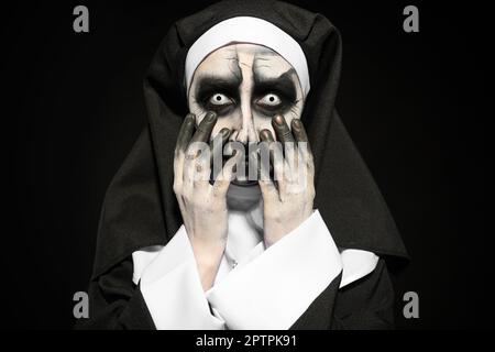 Portrait of scary devilish nun on black background. Halloween party ...